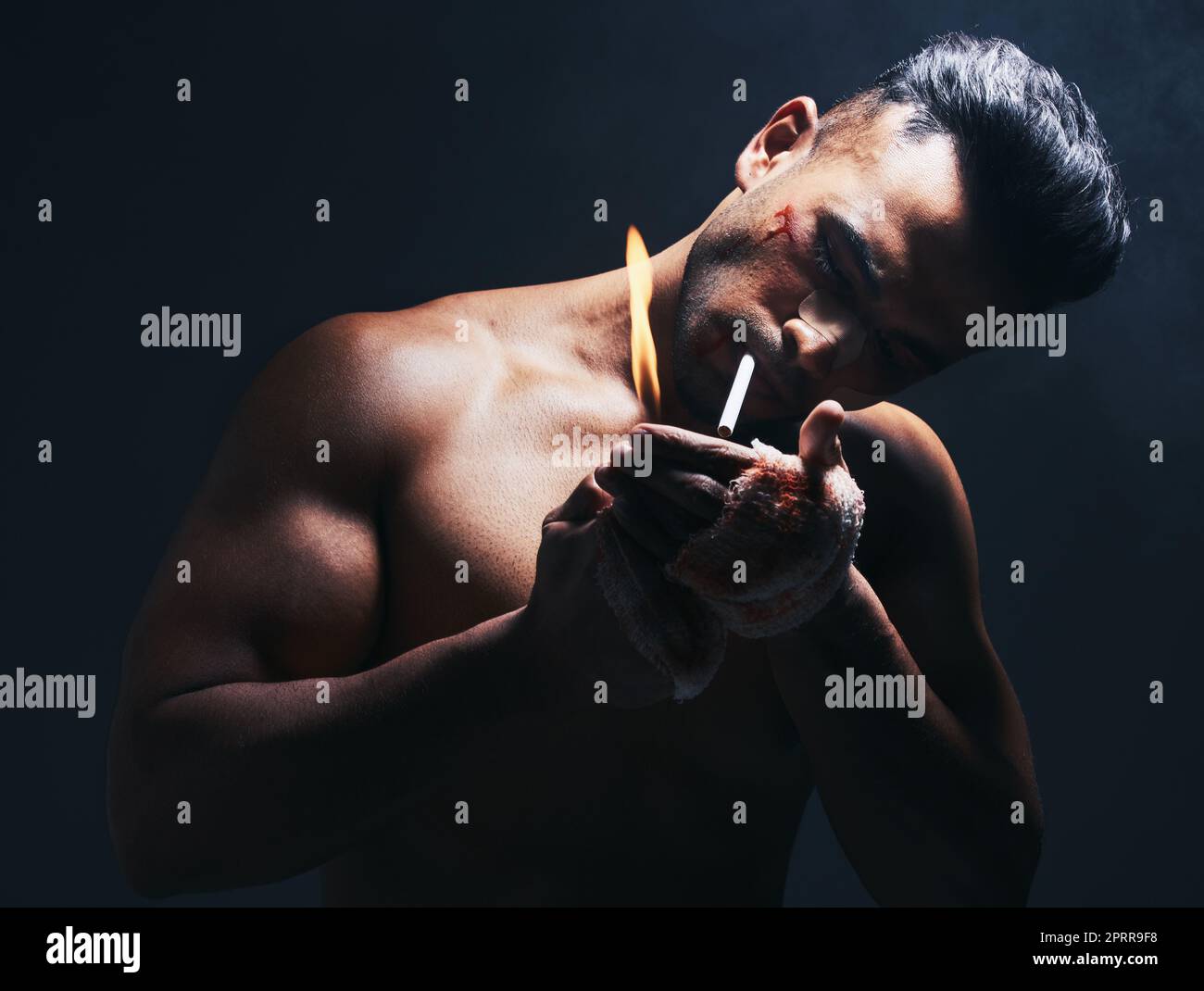 Dark, flame and man lighting a cigarette with a lighter to smoke after a fight in a studio ...