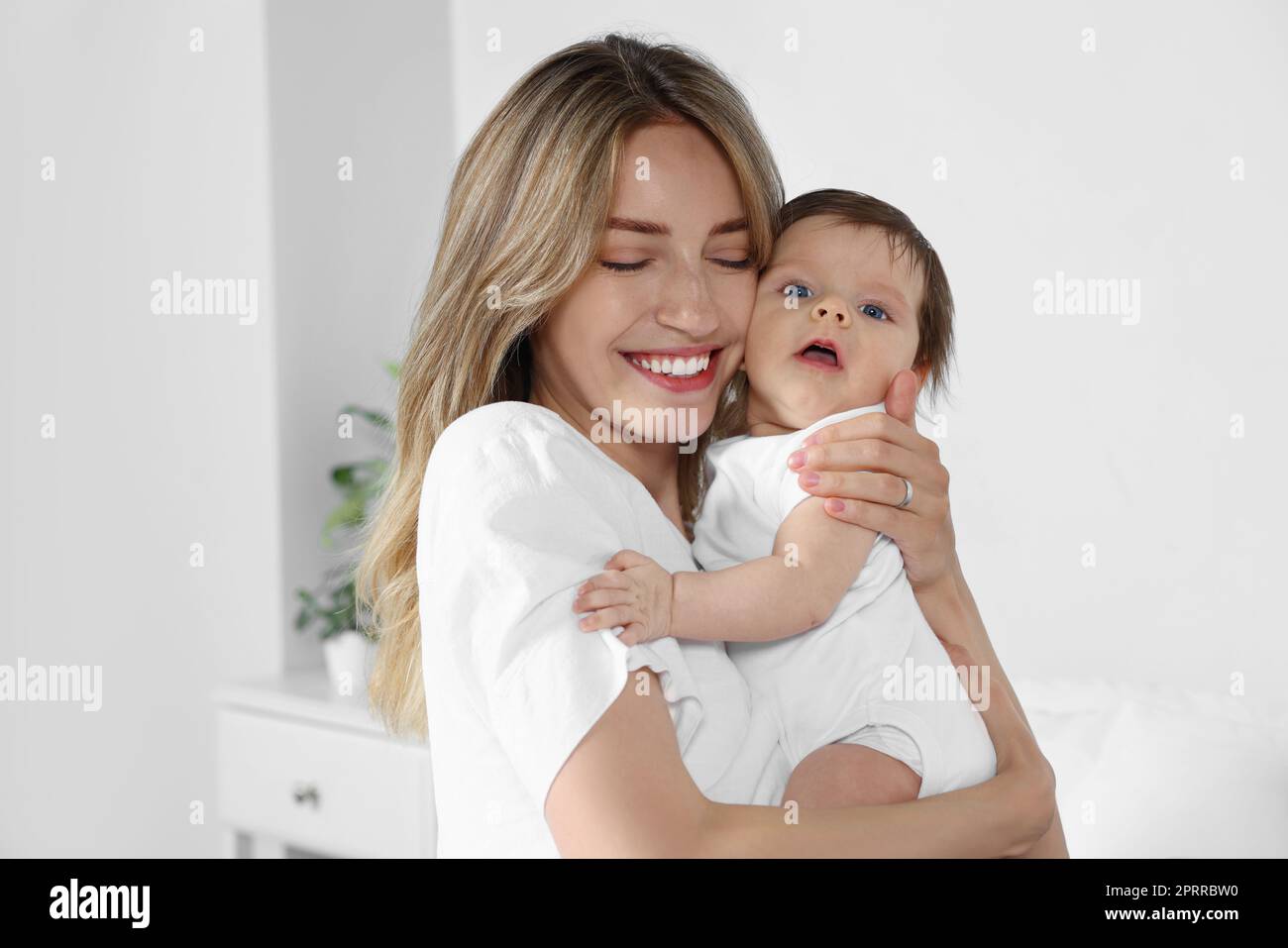 Mother hugging her cute little baby in room Stock Photo - Alamy
