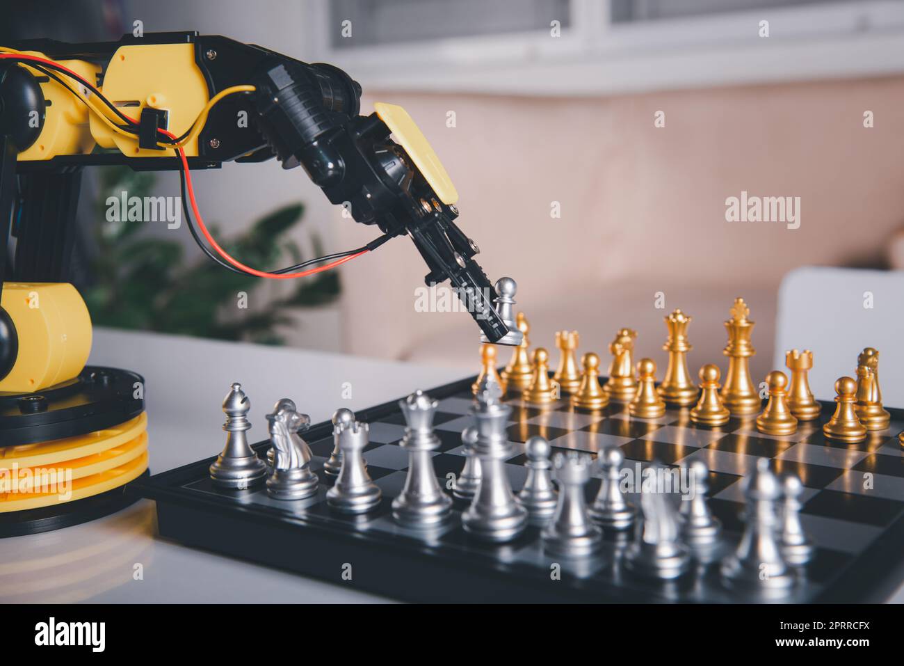 Closeup yellow robot arm playing move chess on chessboard, STEM ...