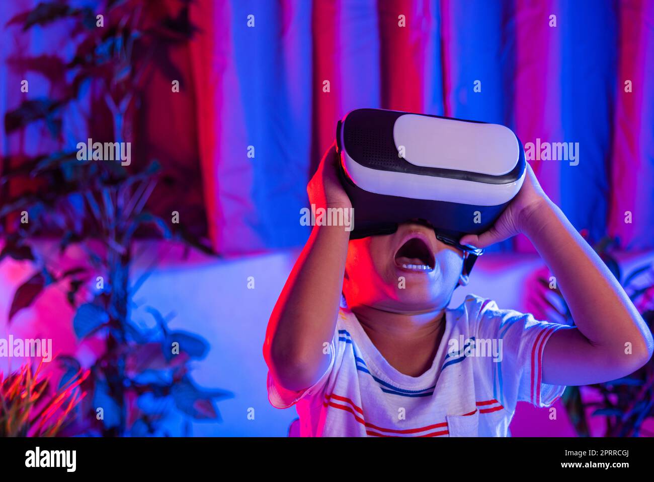 Asian little kid boy wearing virtual reality goggles experiencing ...