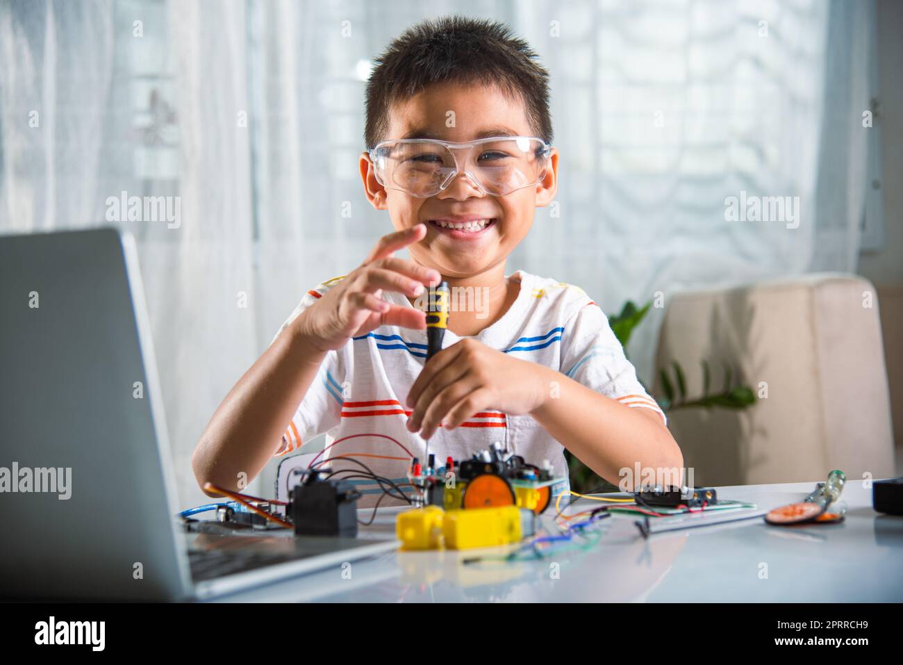 Asian kid boy assembling the Arduino robot car homework project at home ...