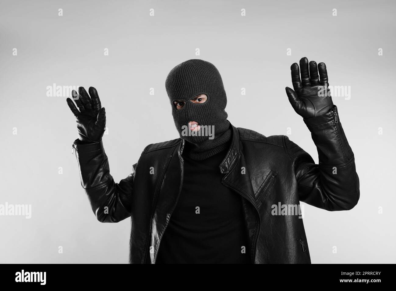 Man wearing knitted balaclava on light grey background Stock Photo - Alamy