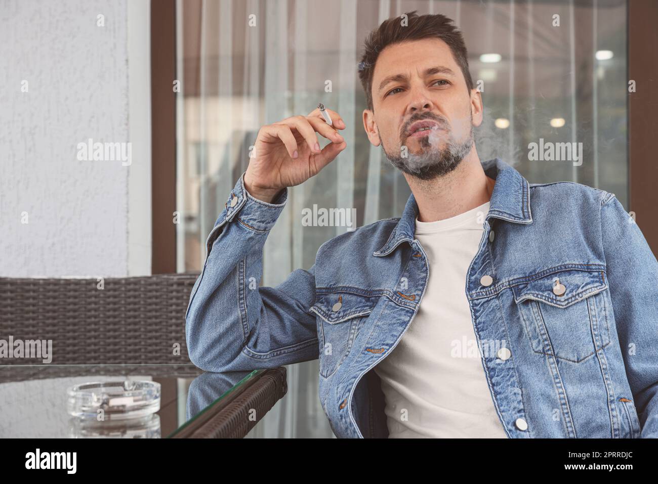 Handsome man smoking cigarette at table in outdoor cafe Stock Photo - Alamy