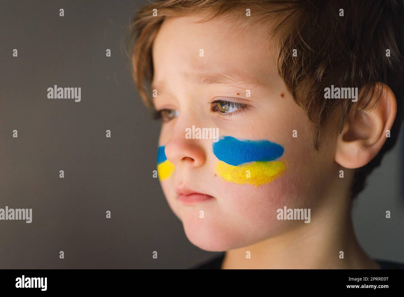 Portrait of a Ukrainian boy with a face painted with the colors of the ...