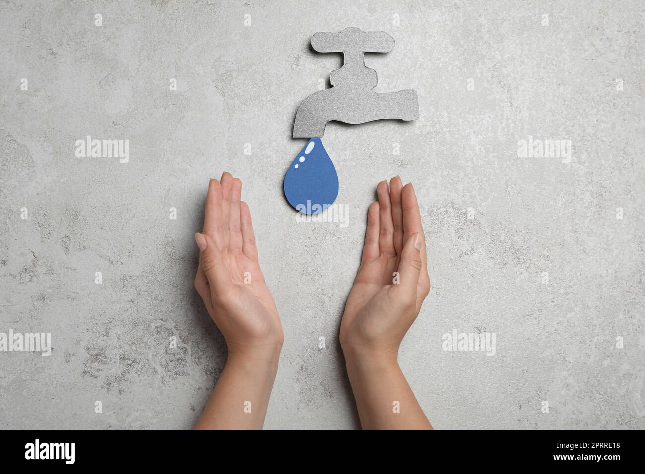 Save Water concept. Woman at light grey table with paper tap and drop ...