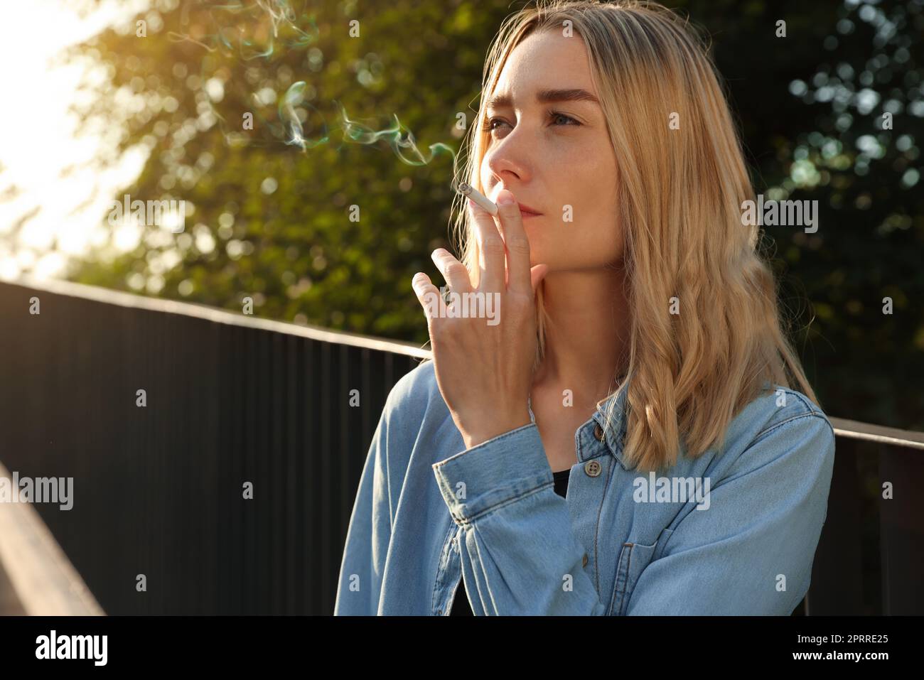 Young woman smoking cigarette outdoors, space for text Stock Photo - Alamy