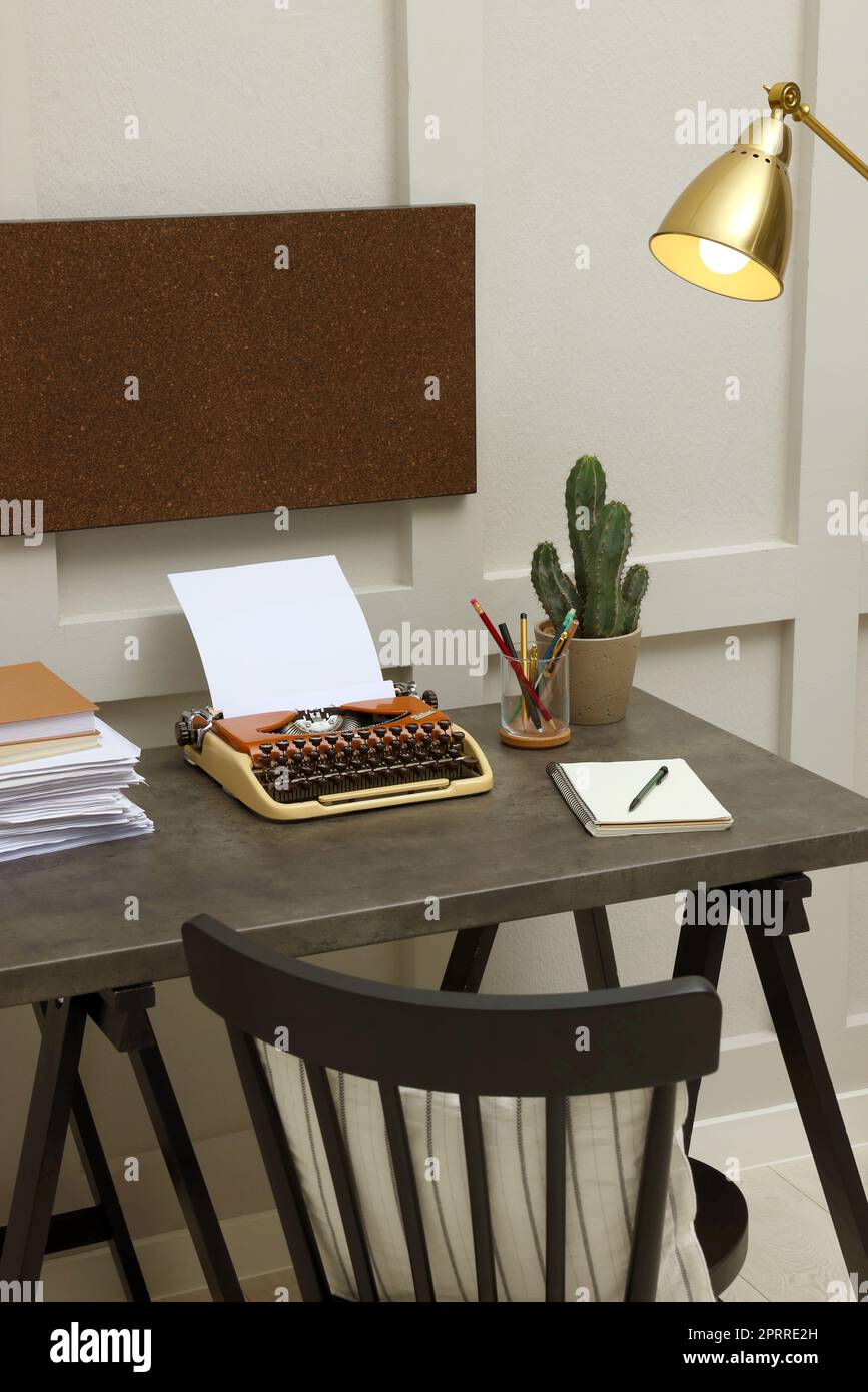 Typewriter and stack of papers on dark table in room. Writer's ...