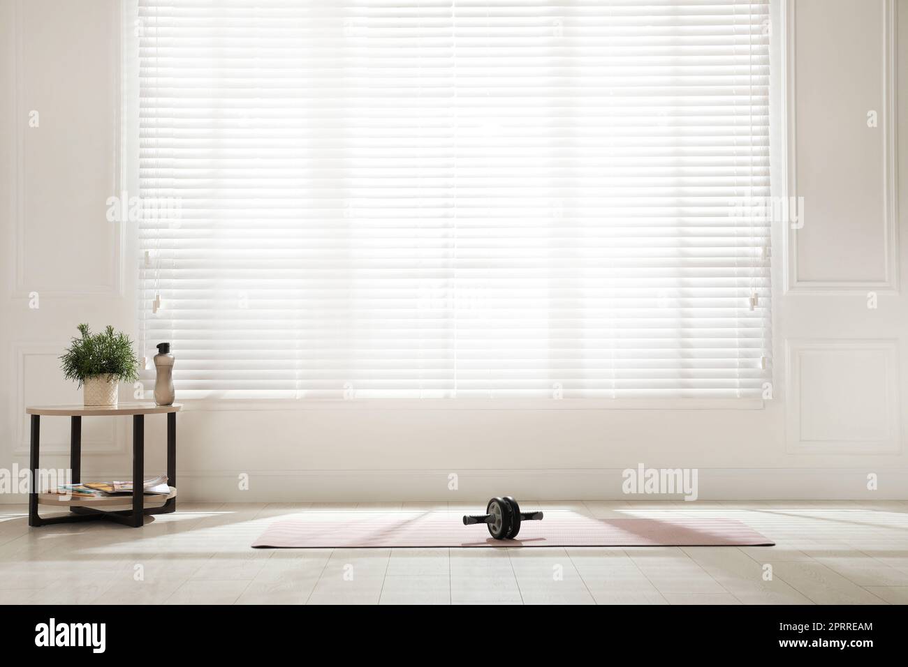 Exercise mat with ab roller near window in spacious room Stock Photo ...