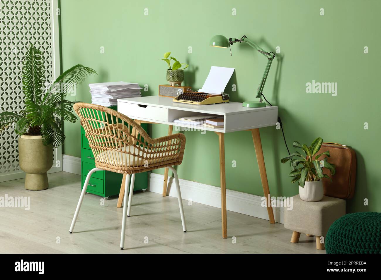 Writer's workplace with typewriter on wooden desk near pale green wall ...