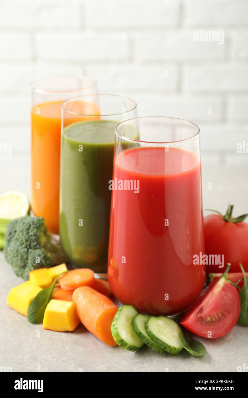 Different tasty juices and fresh ingredients on grey table against ...