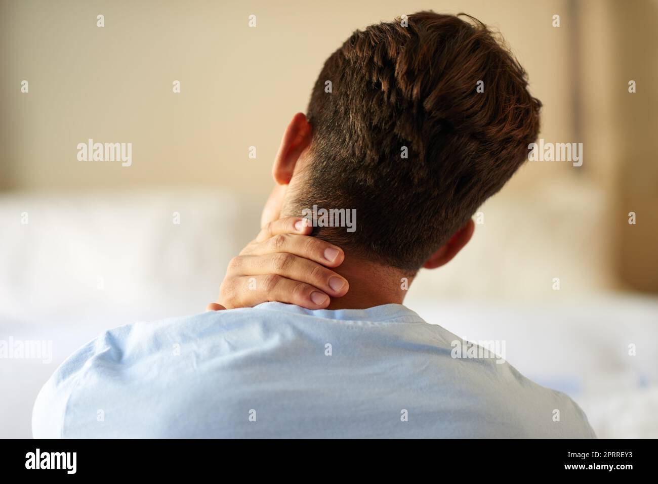 Feeling the tension in his body. Rearview shot of a young man suffering ...