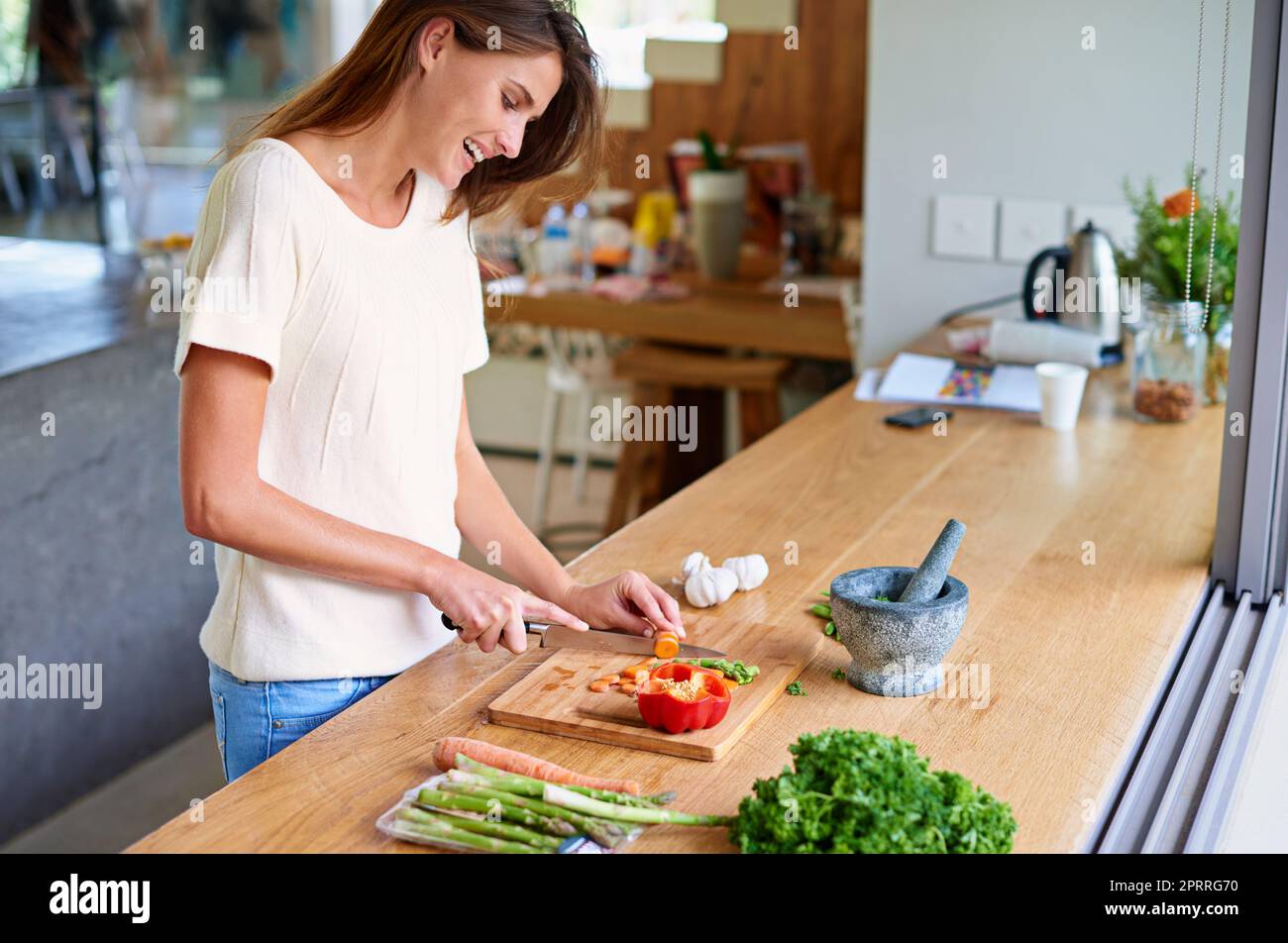 Cooking in progress. an attractive young woman chopping vegetables in a ...