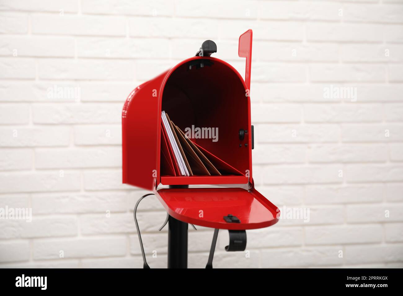 Open red letter box with envelopes near white brick wall Stock Photo ...