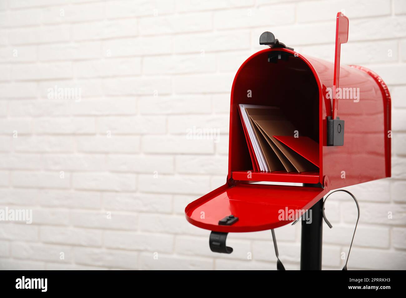 Open red letter box with envelopes near white brick wall. Space for ...