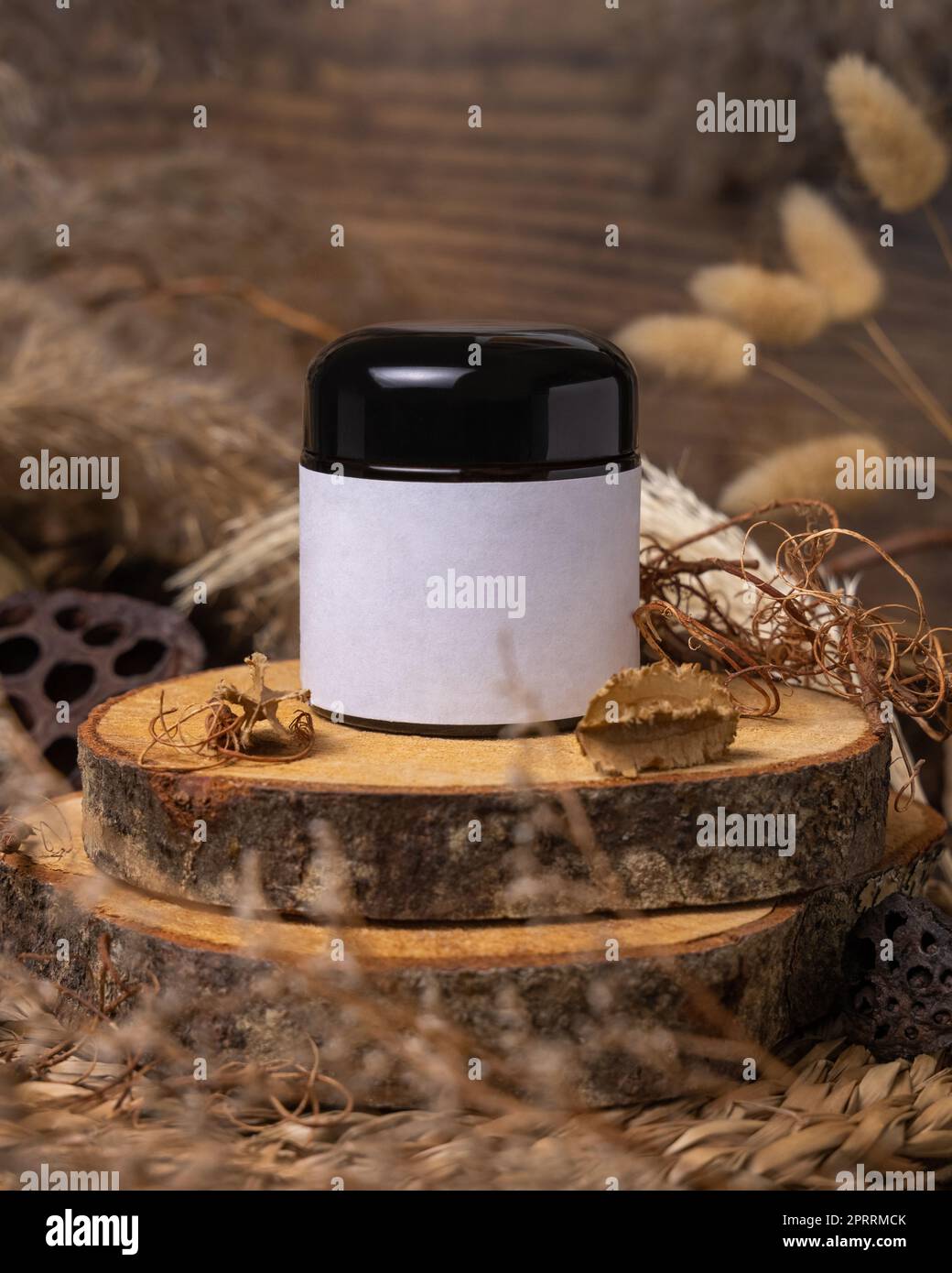 Cream jar with blank label on wood near natural decorations close up ...