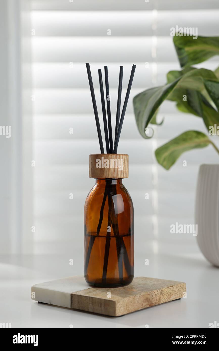 Air reed freshener and houseplant on white table near window Stock ...
