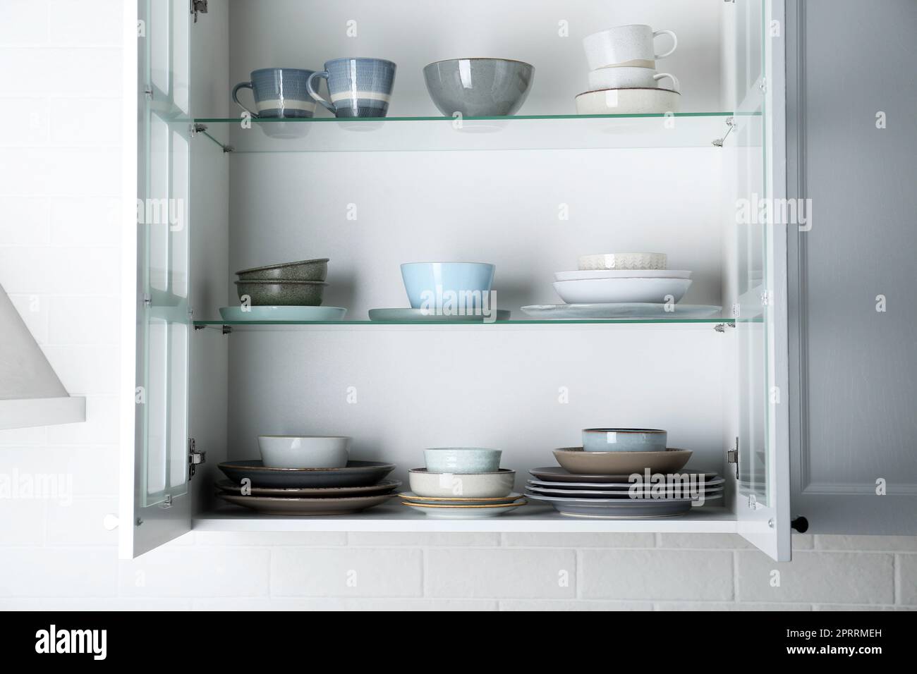 Open cabinet with different clean plates and bowls in kitchen Stock ...
