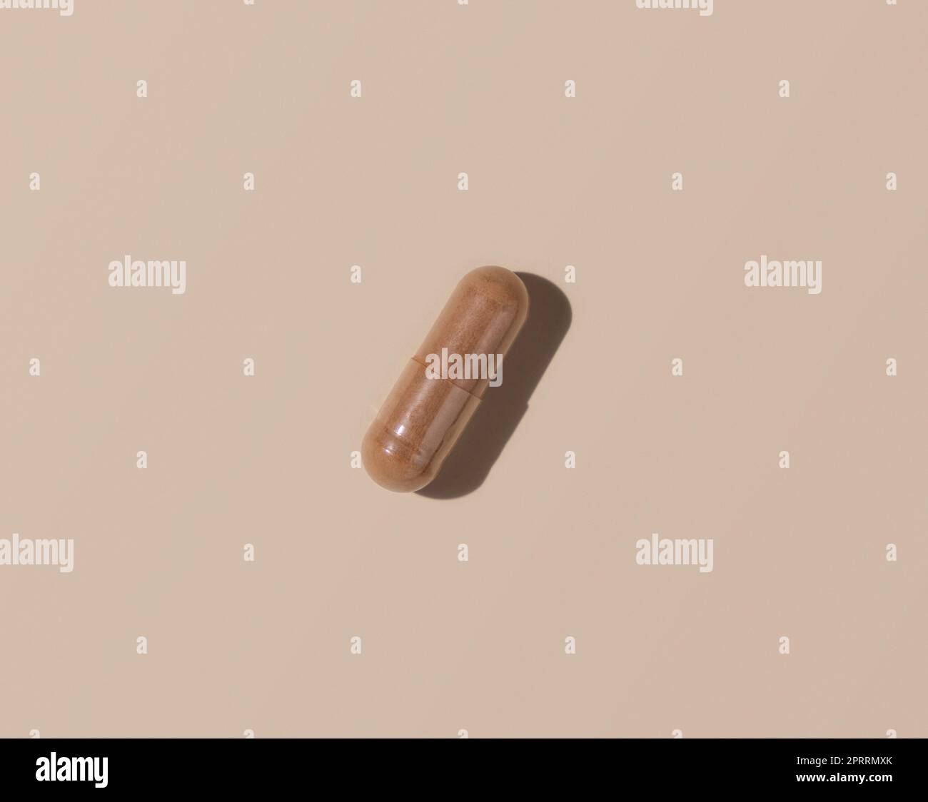 Brown Medical capsule on light beige top view, hard shadows. Taking ...