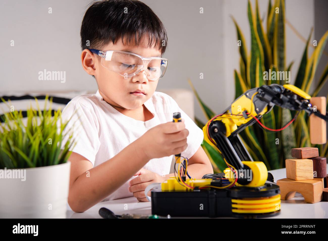 Happy Asian little kid boy using screwdriver to fixes screws robotic ...