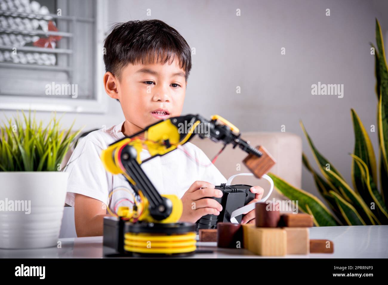 Happy Asian little kid boy using remote control playing robotic machine ...