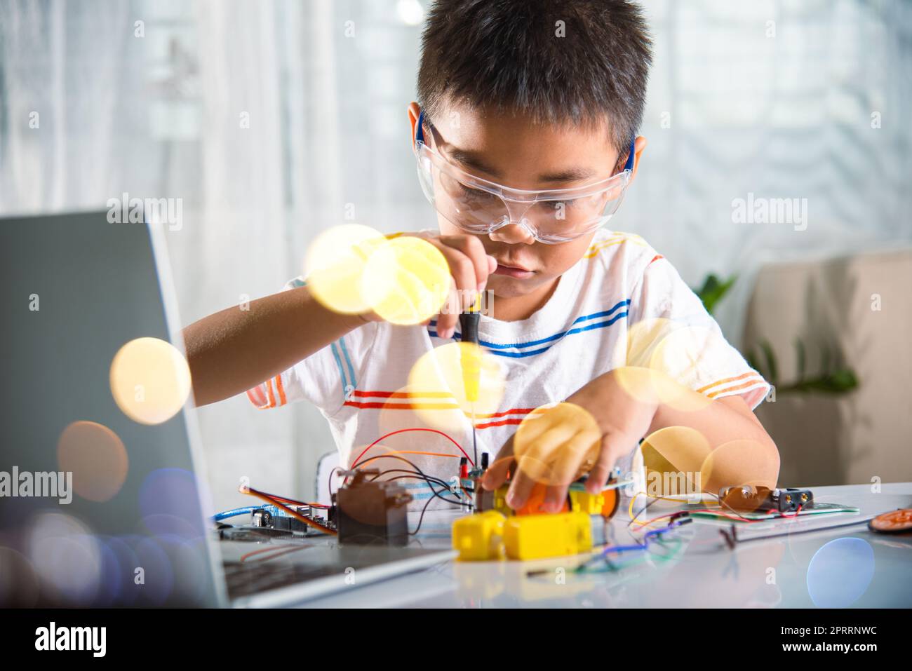 Asian kid boy assembling the Arduino robot car homework project at home ...