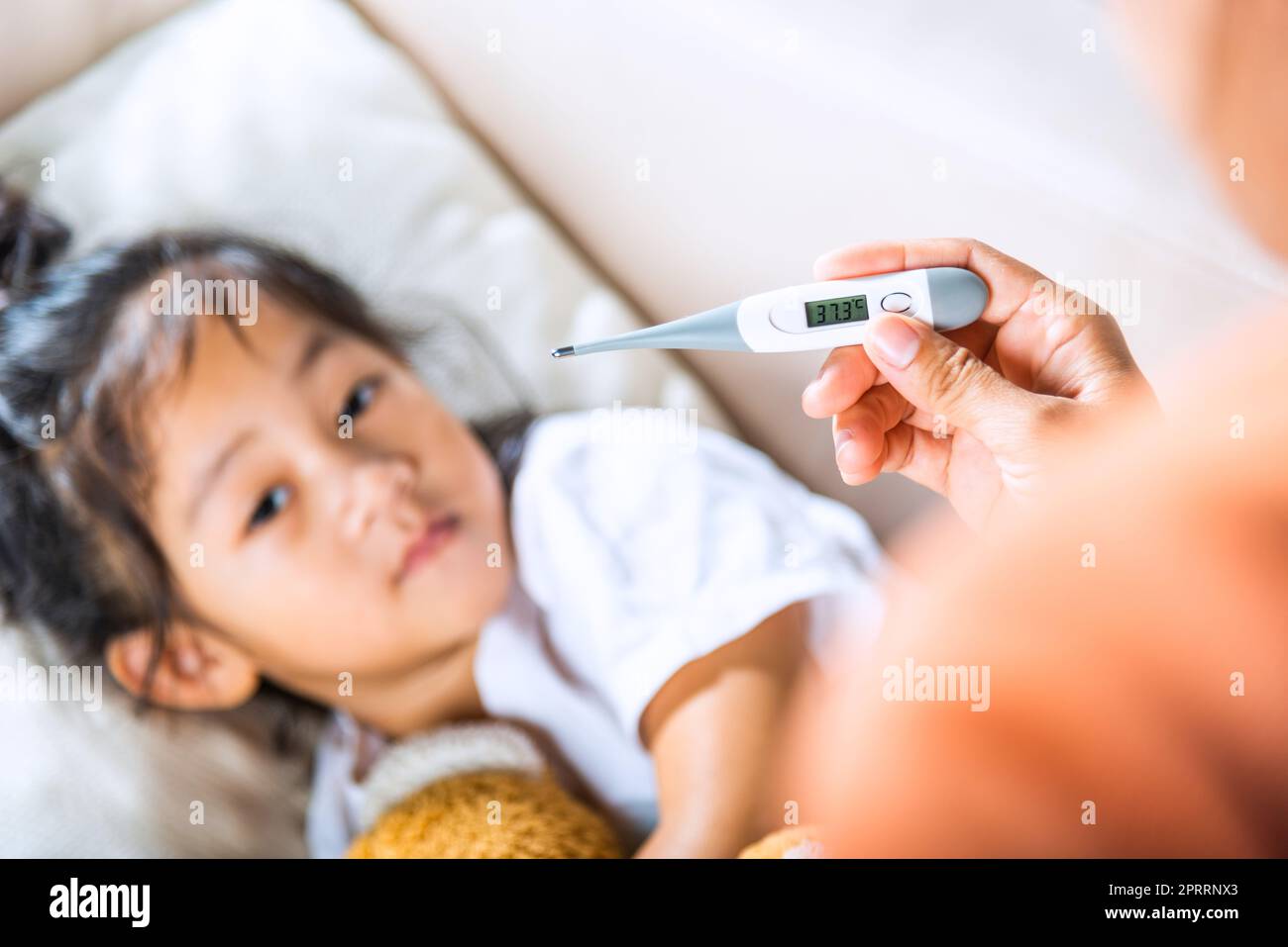 Mother checking temperature of her sick daughter with thermometer in mouth Stock Photo - Alamy