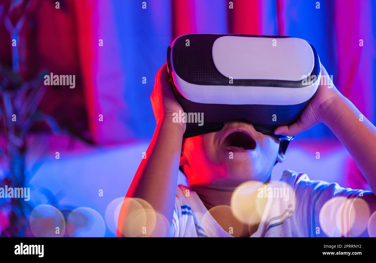 Asian little kid boy wearing virtual reality goggles experiencing ...