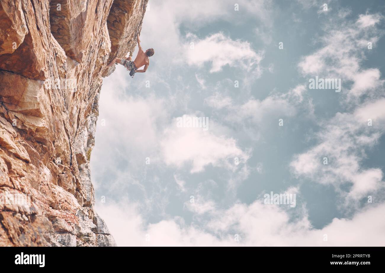 Rock climbing, sports and adventure with man on mountain against a blue ...