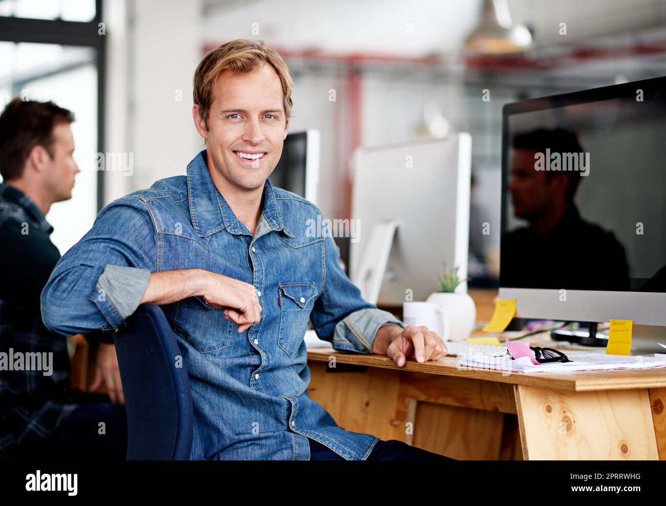I design my own success. Portrait of a designer sitting at his desk in ...