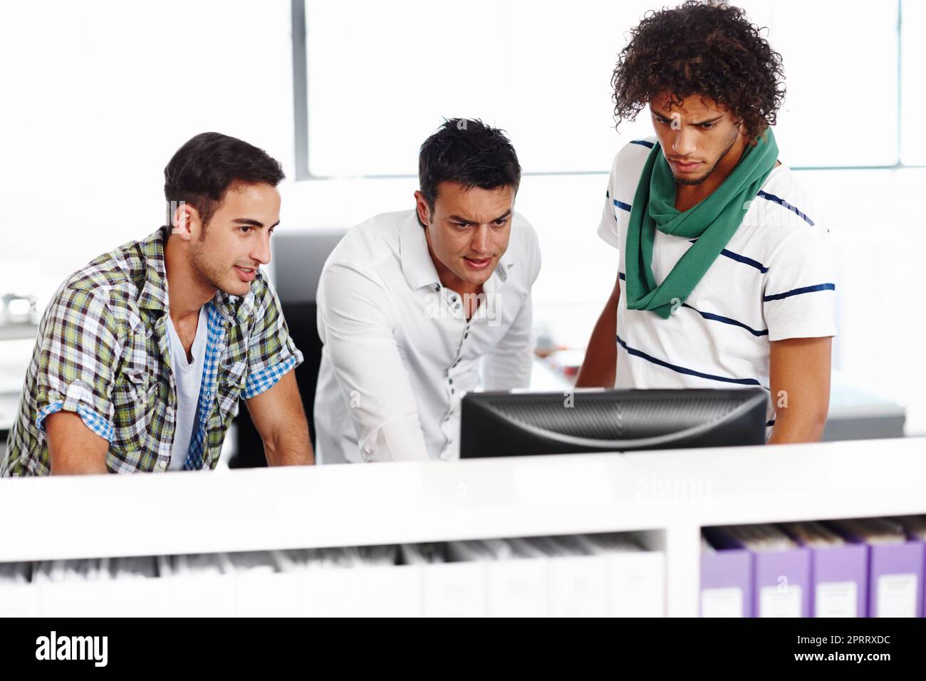 Discussing the new web design. Three male colleagues working in the ...