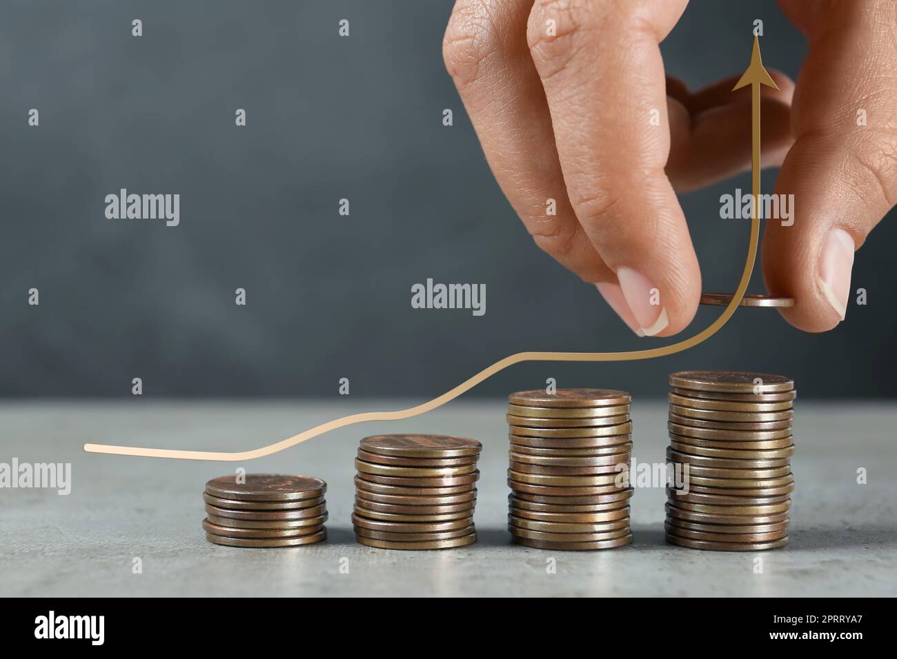 Salary increase concept. Woman stacking coins on grey table and ...