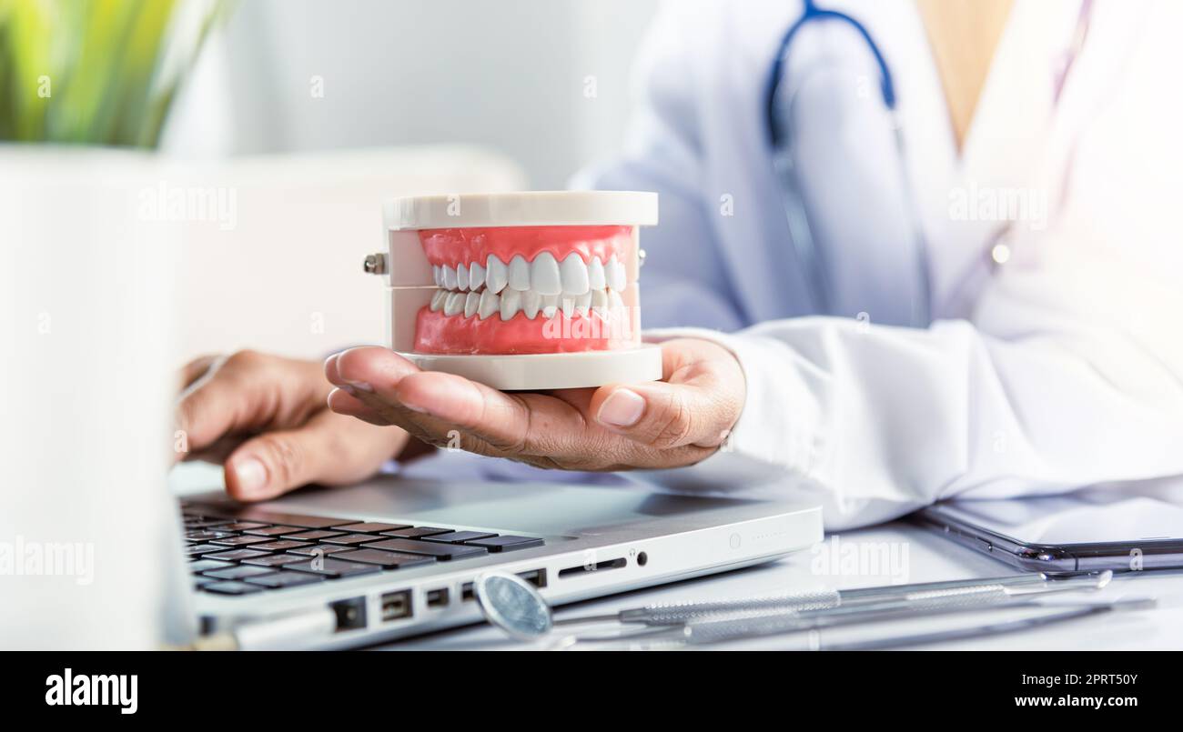 Oral dental hygiene. Female doctor sitting and hold tooth on desk at ...