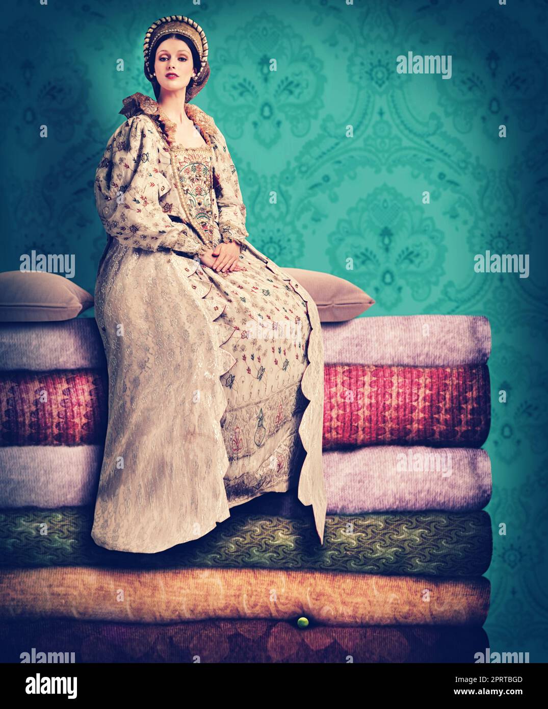 A bed fit for a queen. Portrait of a regal queen sitting on a stack of ...