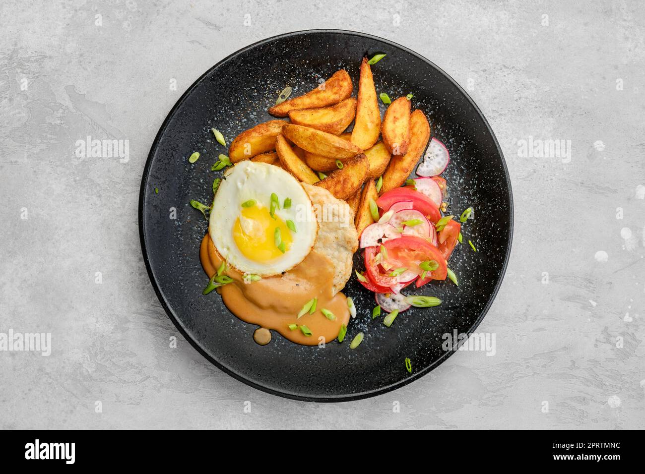Top view of chopped pork sirloin with fried potato wedges, egg, tomato ...
