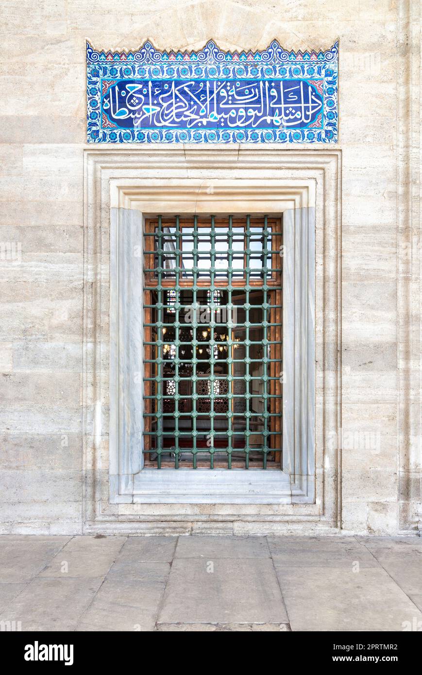 Decorated wrought iron window, in a stone wall, at the courtyard of ...