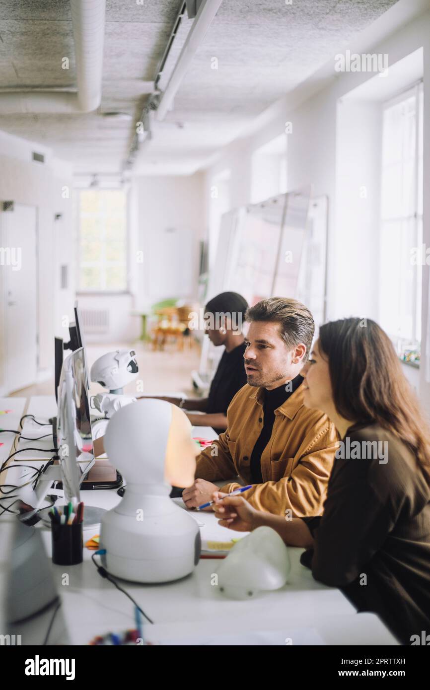 PhD students discussing over computer in innovation lab Stock Photo - Alamy