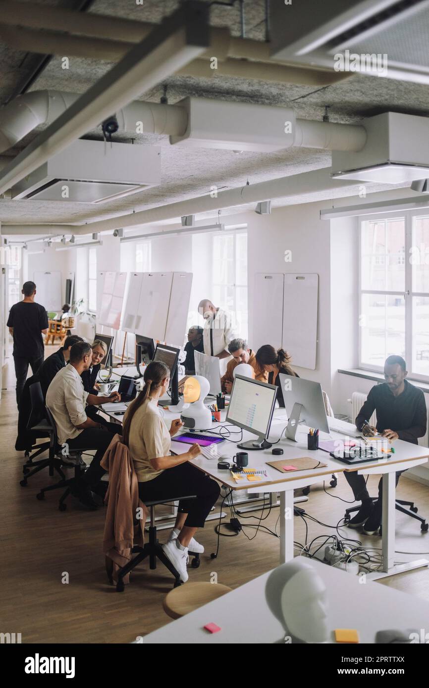 Multiracial students and professors discussing at computer desk in ...