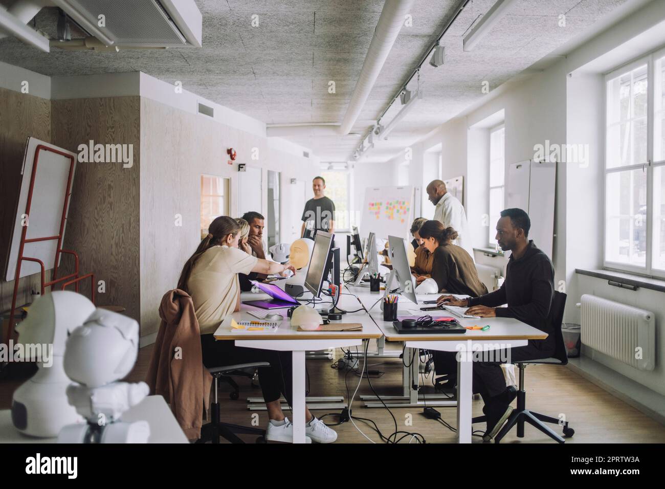 Male and female professors discussing with PhD students at computer ...