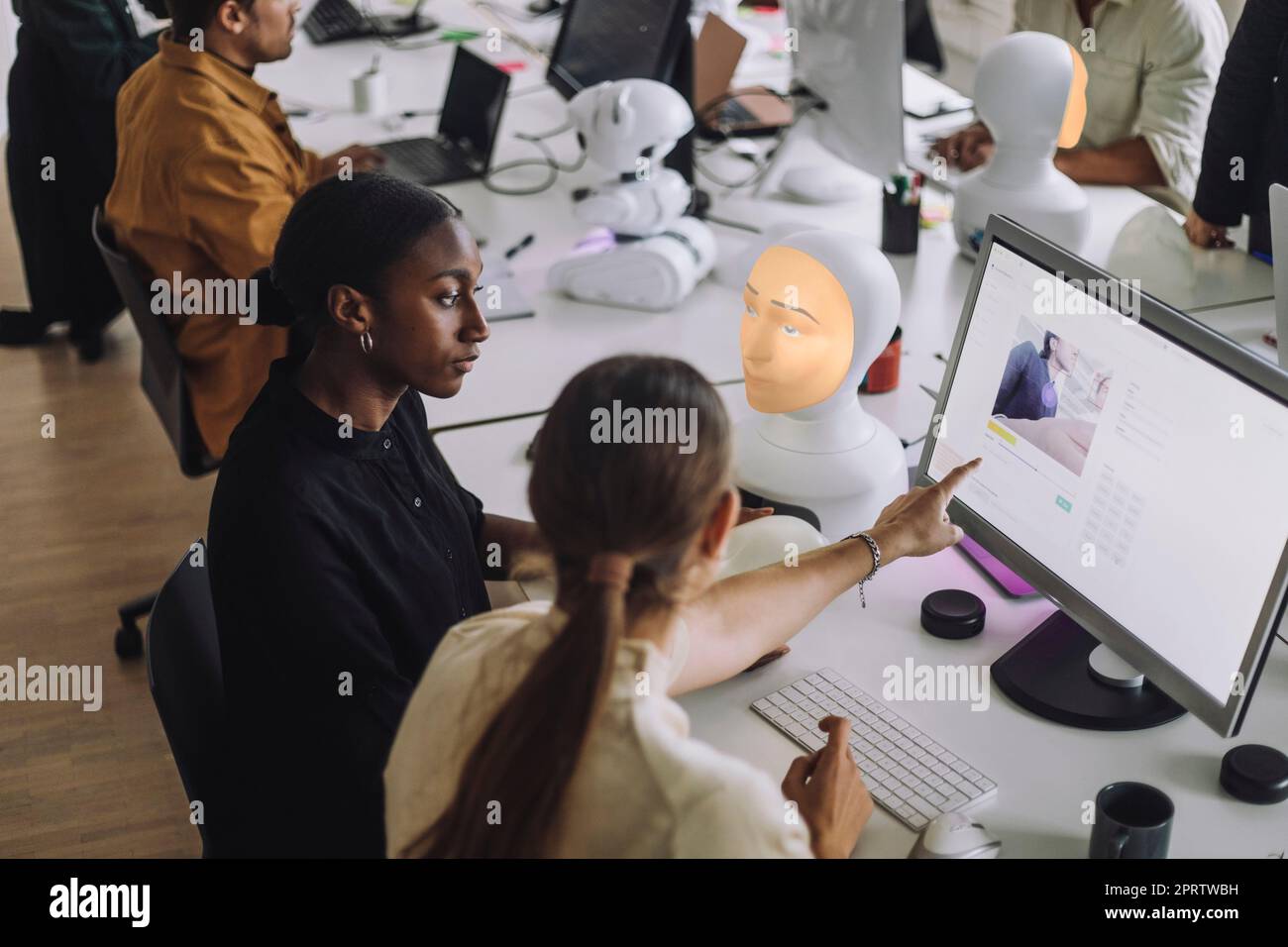 Multiracial female PhD students discussing over computer in innovation ...