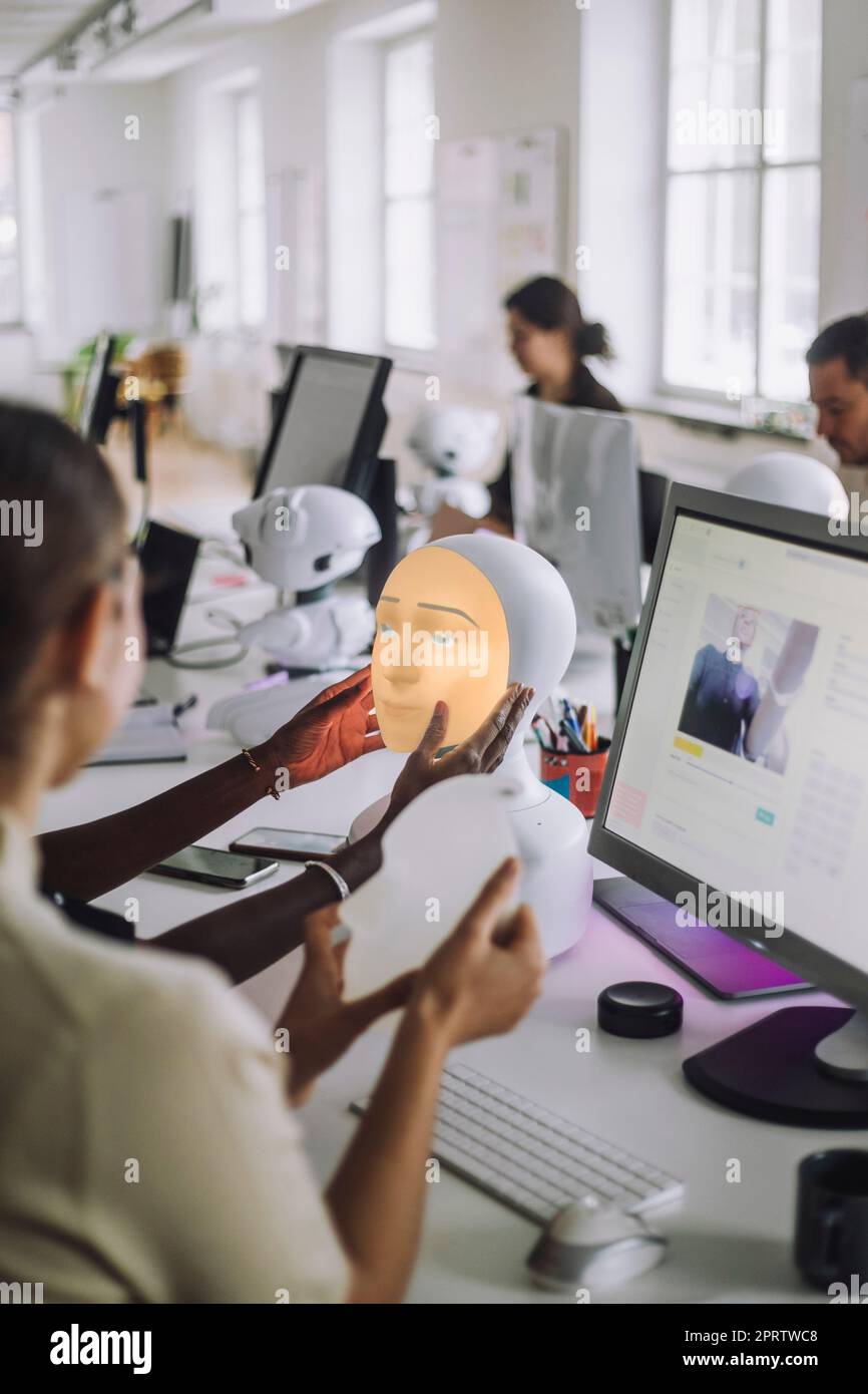 Female PhD students discussing over social robot while sitting at desk ...