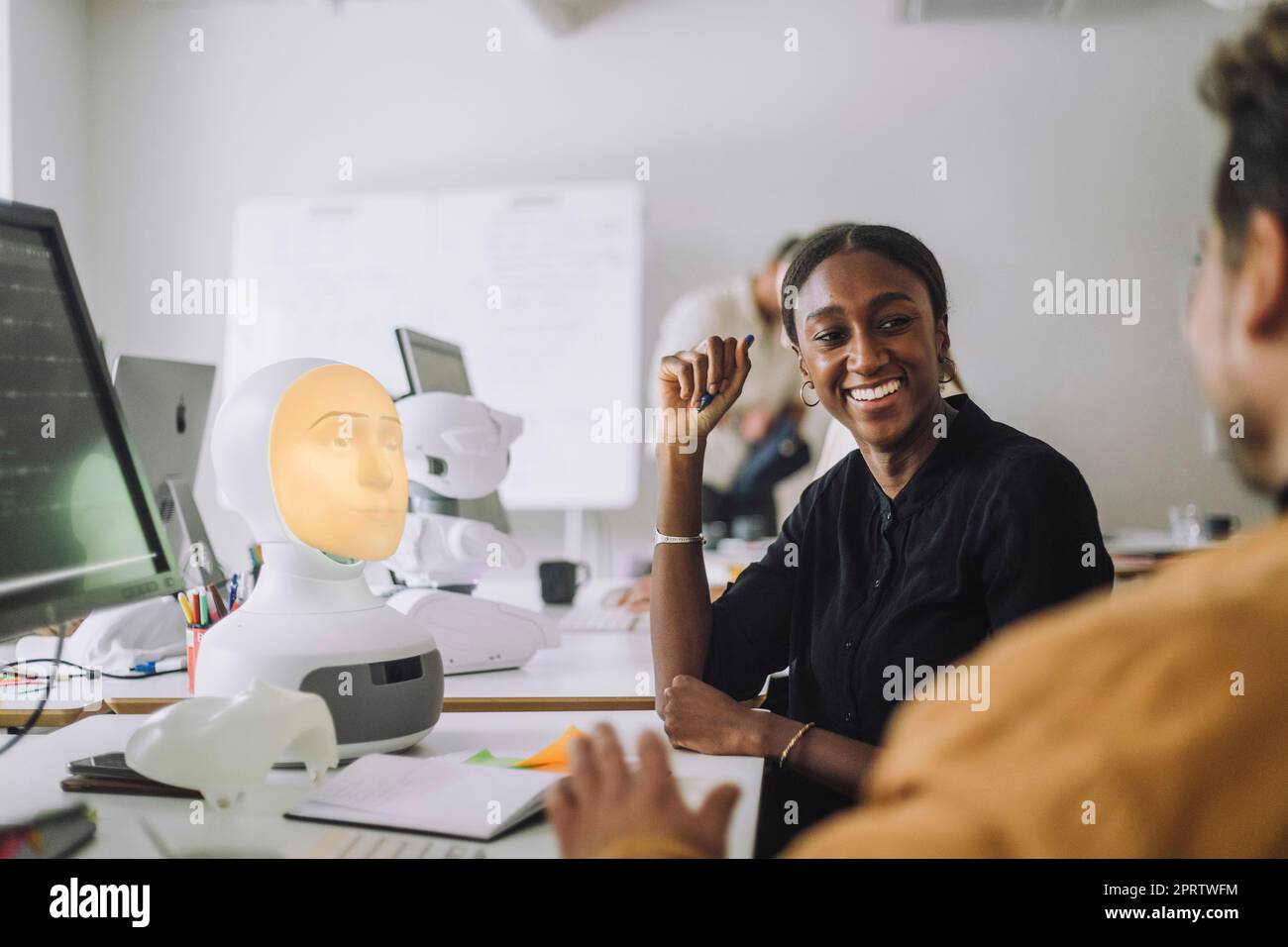 Smiling female PhD student discussing with man at desk in innovation ...