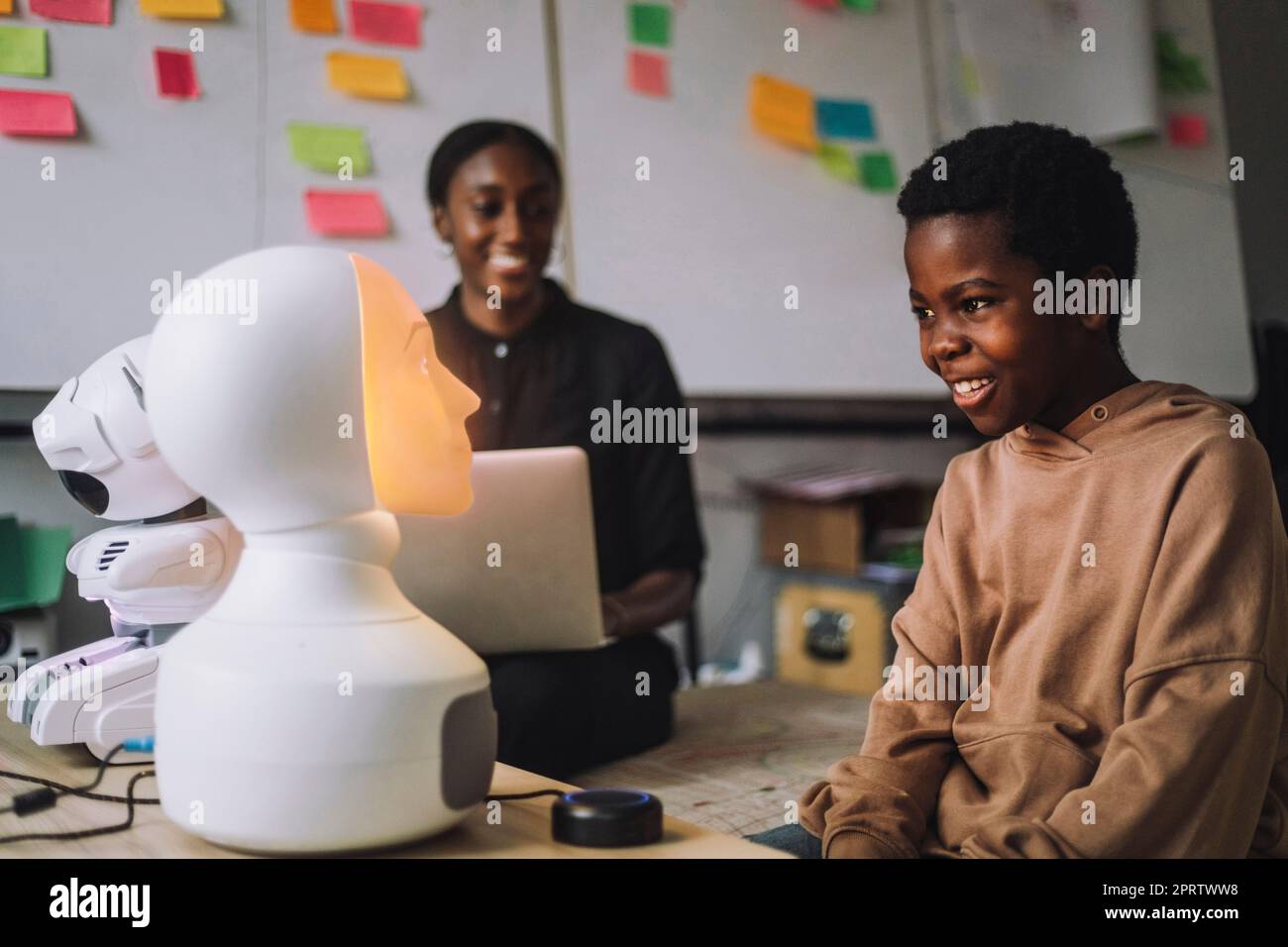 Happy student communicating with illuminated social robot at innovation ...
