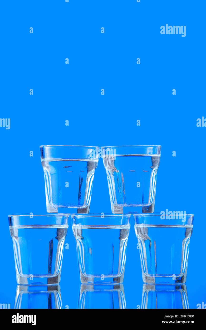 front view water glasses stacked on top of each other on blue ...