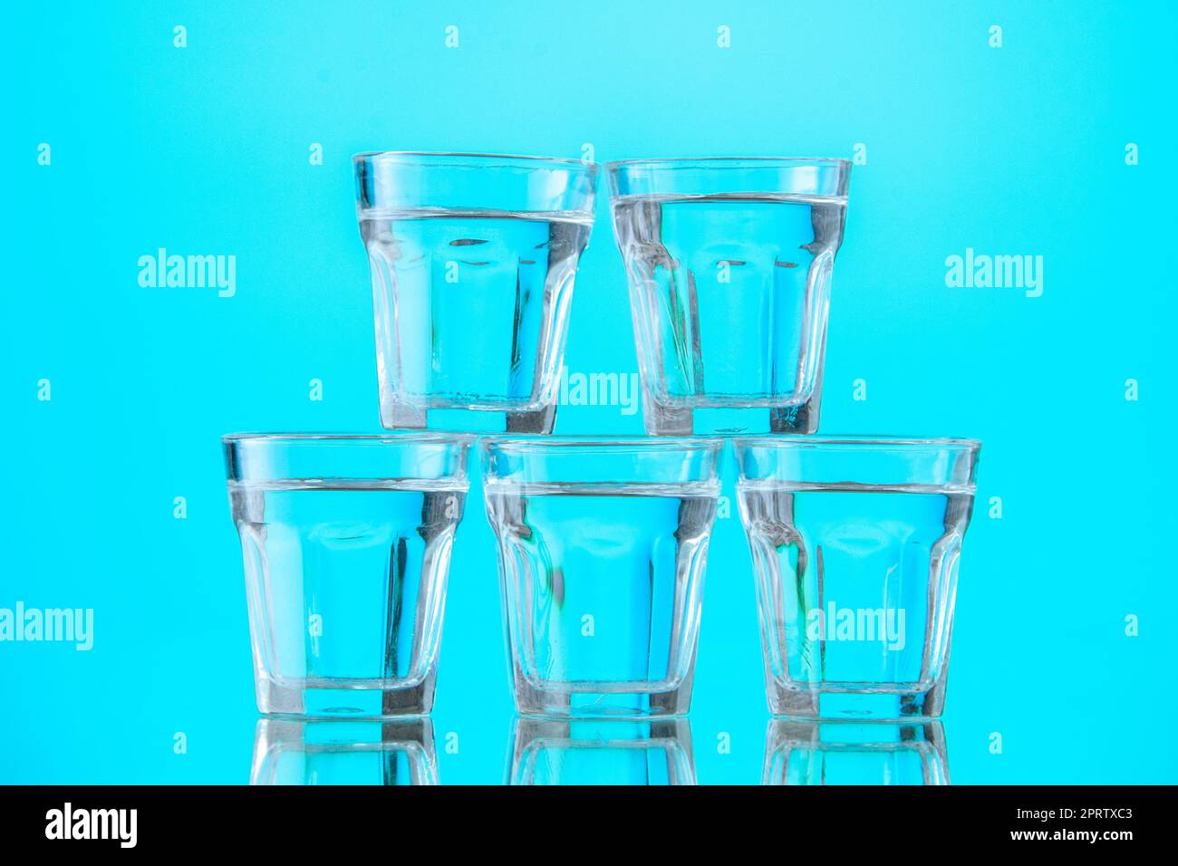 front view water glasses stacked on top of each other on light blue ...
