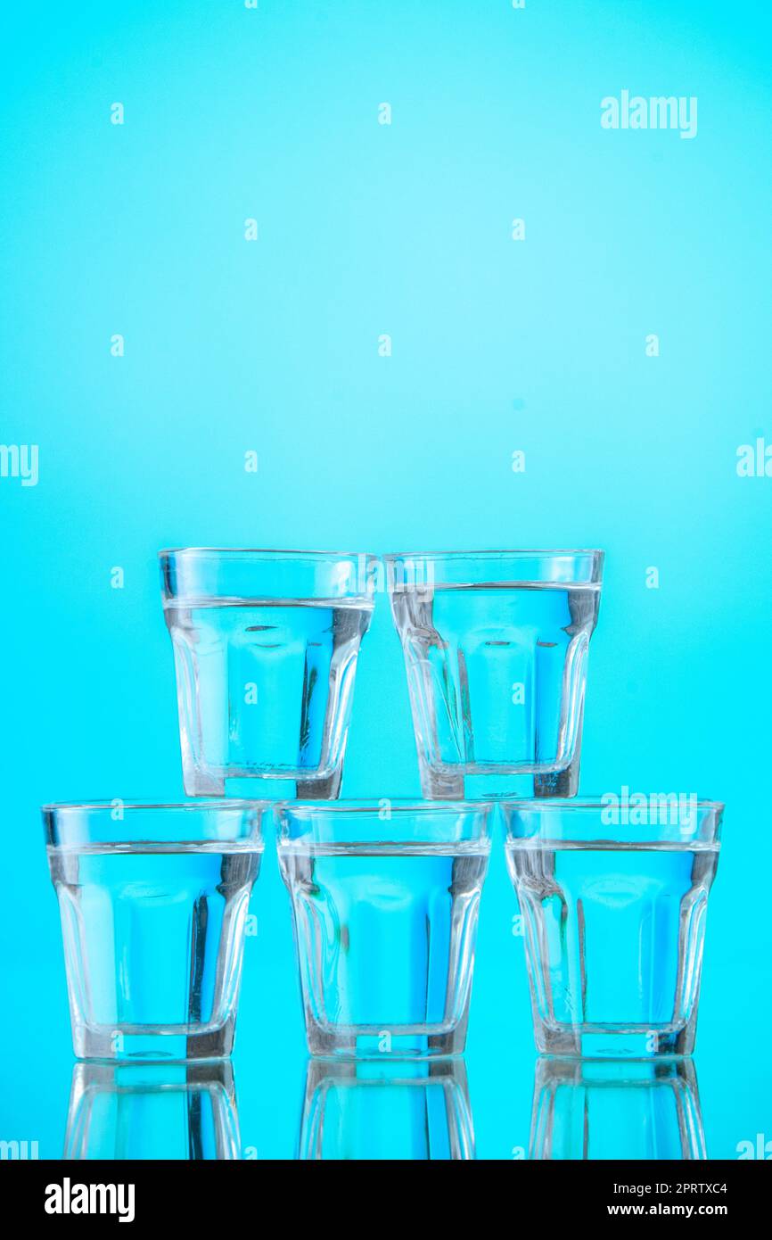 front view water glasses stacked on top of each other on light blue ...