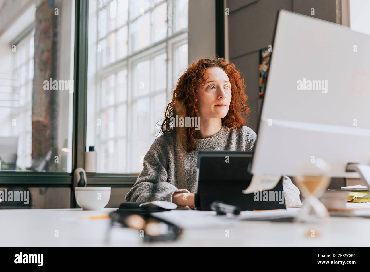 Focused redhead businesswoman working on desktop PC at office Stock ...