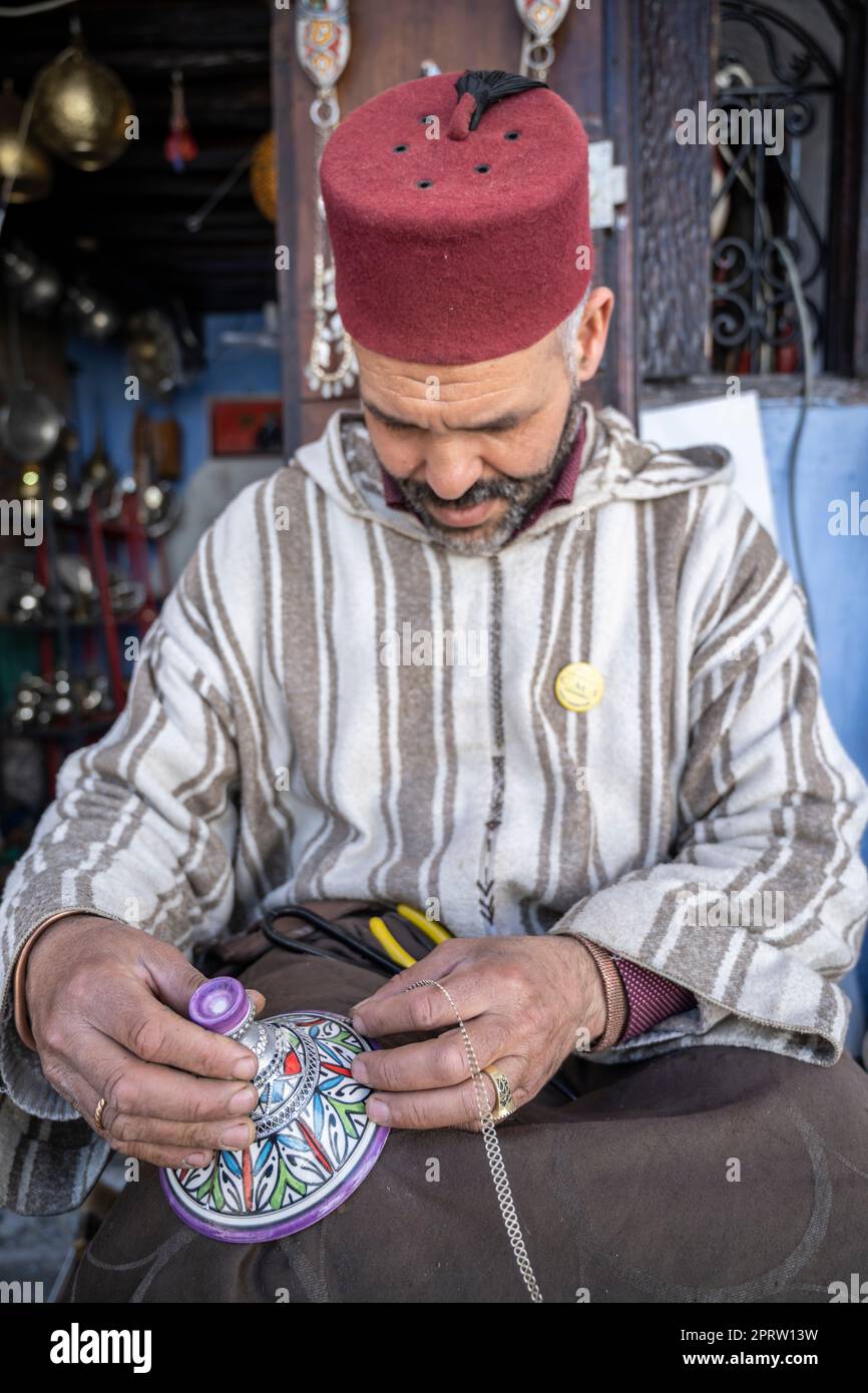 Craftsman dressed in djellaba and typical Moroccan hat working in the ...