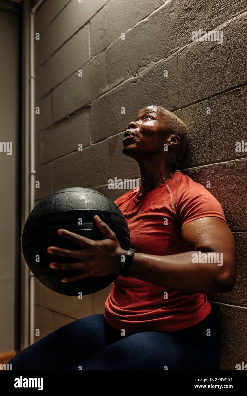 Dedicated female athlete holding medicine ball while doing wall sit ...