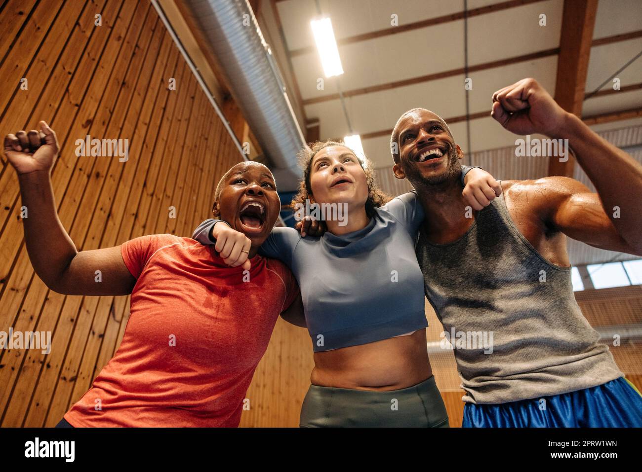 Low angle view of male and female athletes cheering together at sports ...