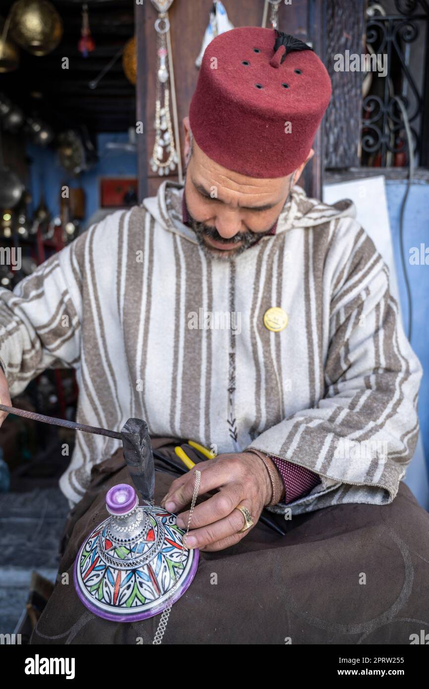 Craftsman dressed in djellaba and typical Moroccan hat working in the ...